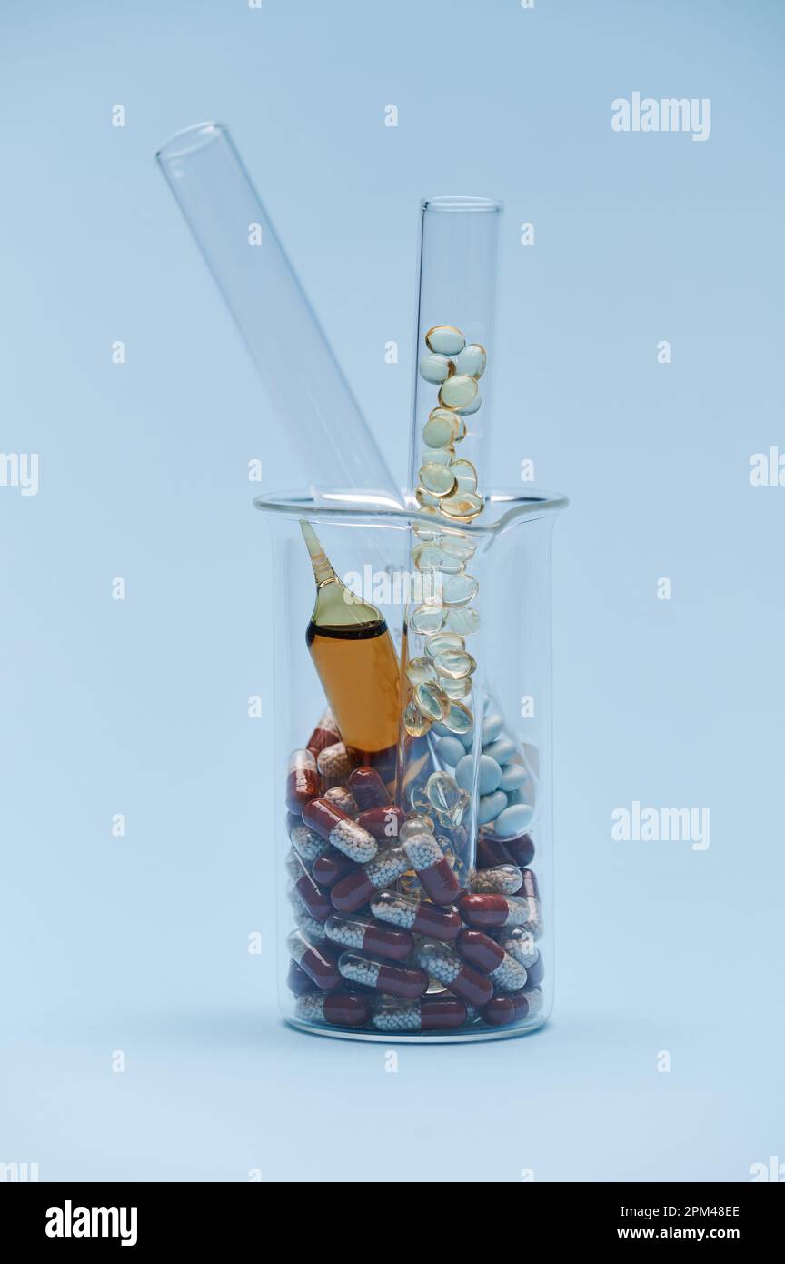 Graduated laboratory beaker with pills, ampoule and test tubes with ...