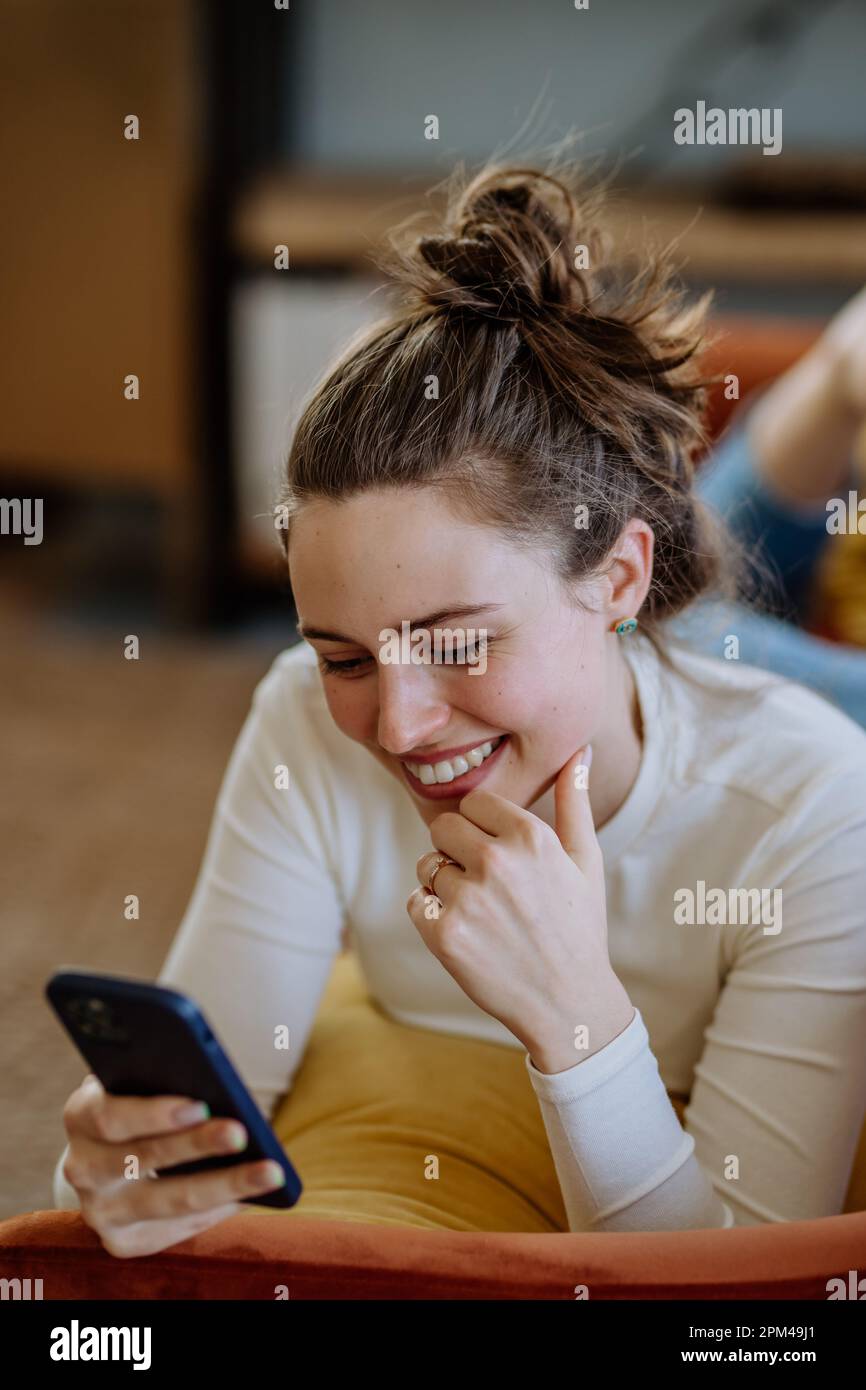 Young woman scrolling her smartphone in the apartment Stock Photo - Alamy