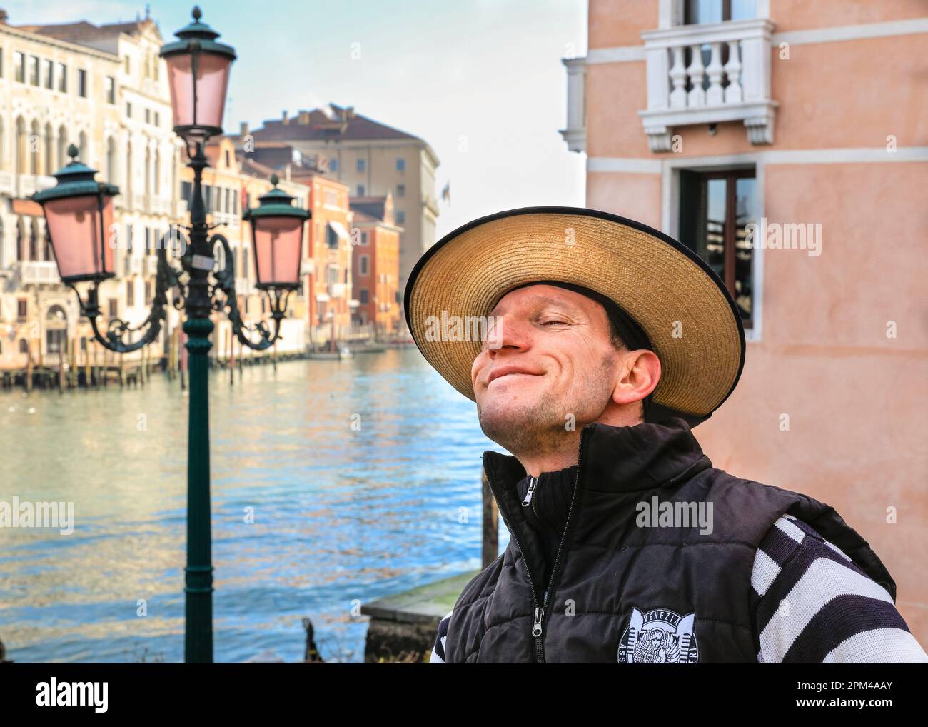 Venetian gondoliere with typical hat smiles by the Grand Canal, Venice ...