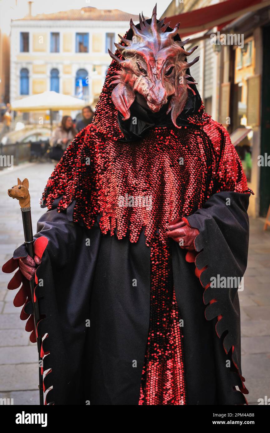 Venice carnival, costumed participant in demon mask and red and black ...