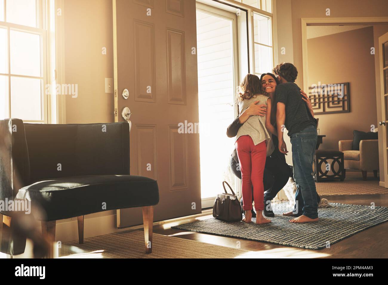 We missed you Mommy. a mother arriving home to a loving welcome from her son and daughter Stock ...