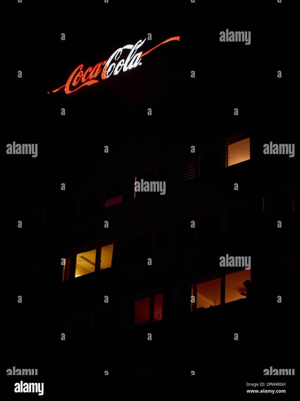 A Coca-Cola logo visible at night, illuminated by bright lights against ...