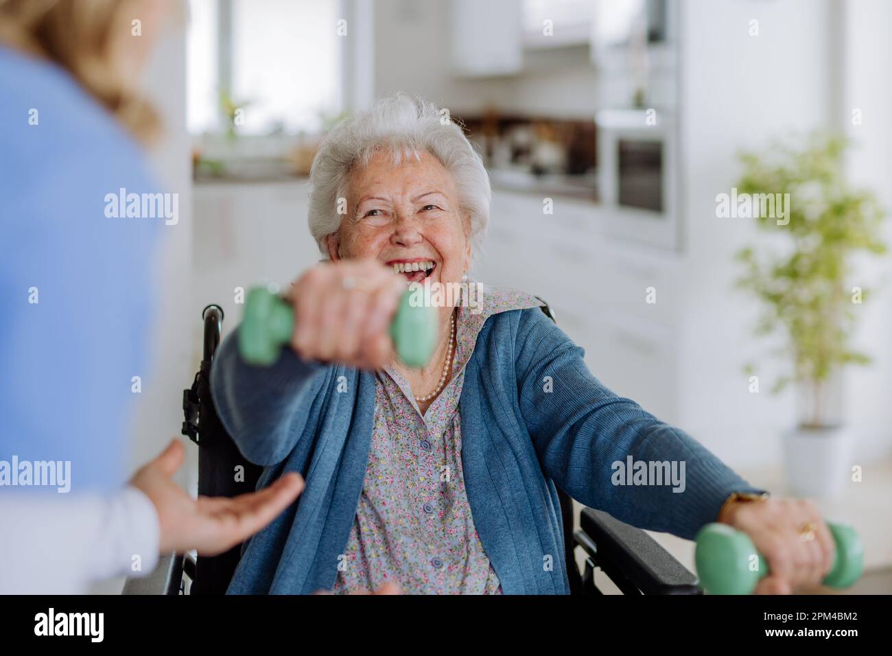 Nurse exercising with senior woman at her home, concept of healthcare ...