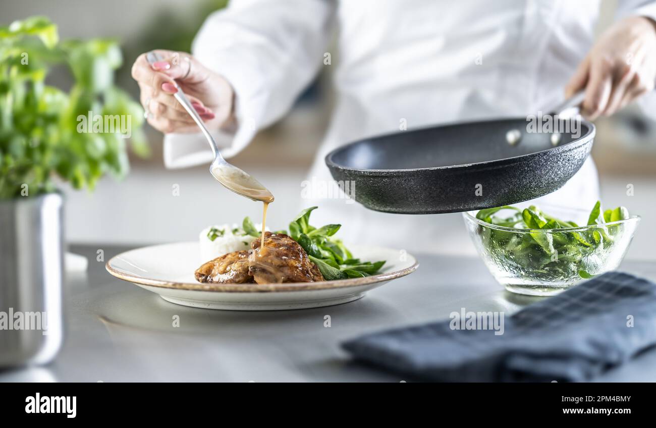 Female cook finishing food with sauce on counter in restaurant or hotel ...