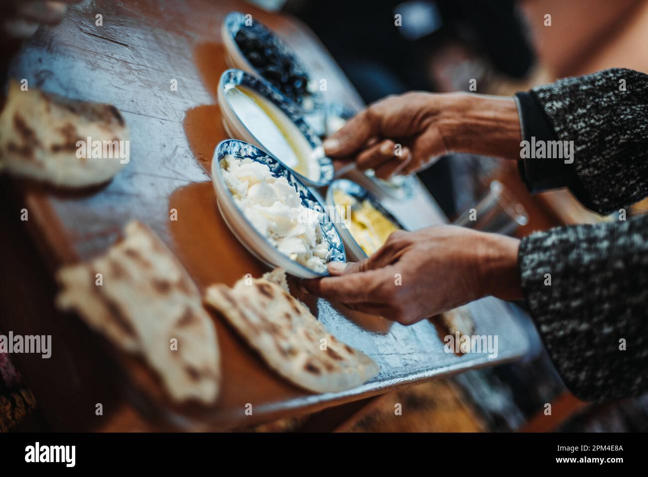An elderly person setting up a table for a meal, arranging dishes ...