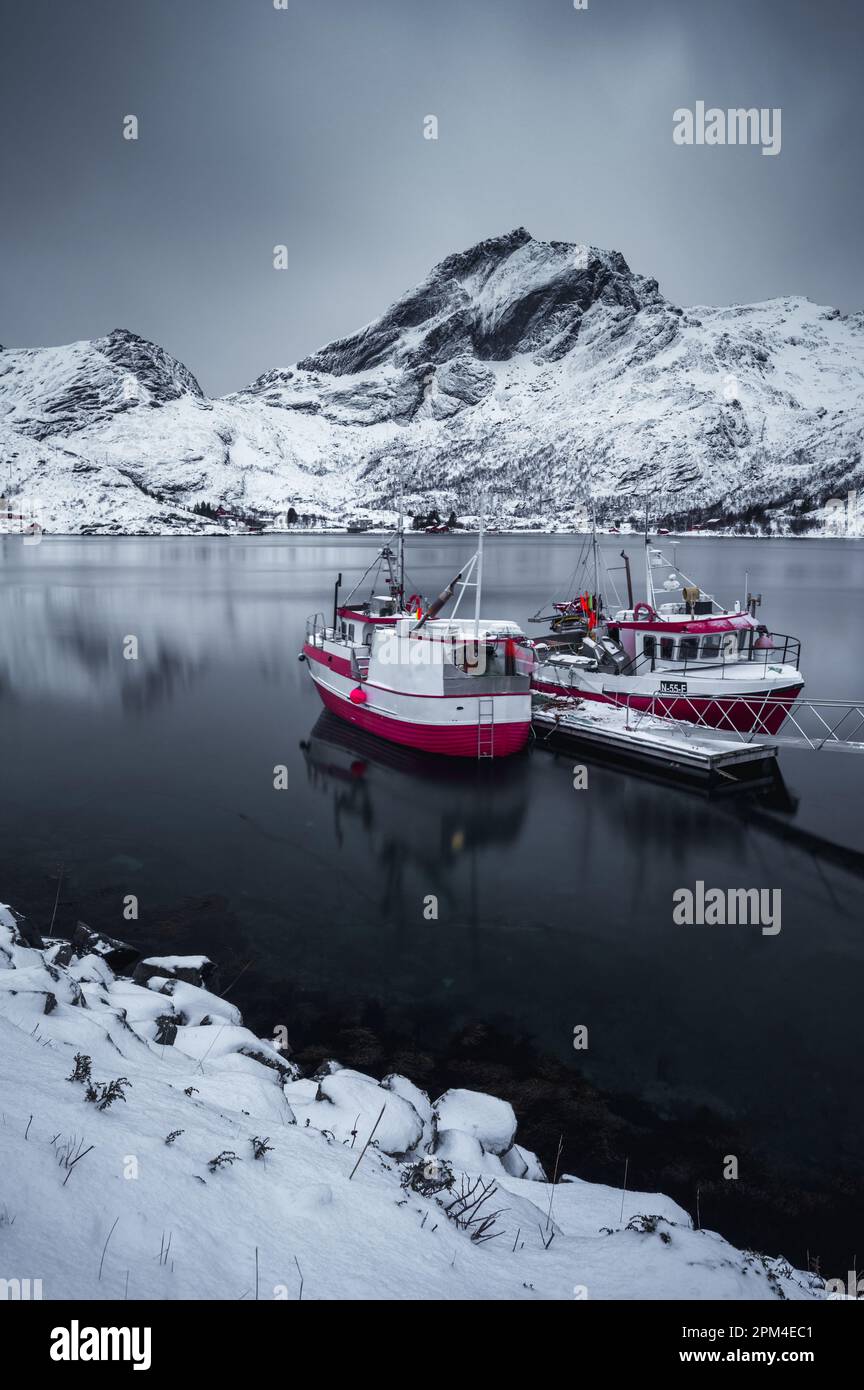 Two marina vessels docked in a calm coastal harbor surrounded by ...