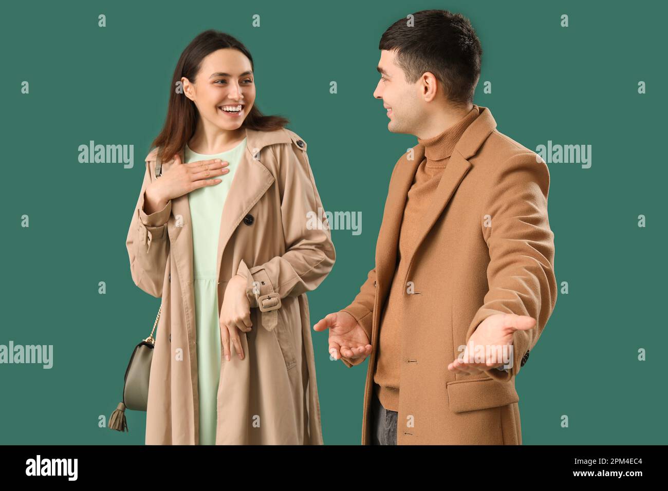 Young man letting beautiful woman go first on green background Stock ...