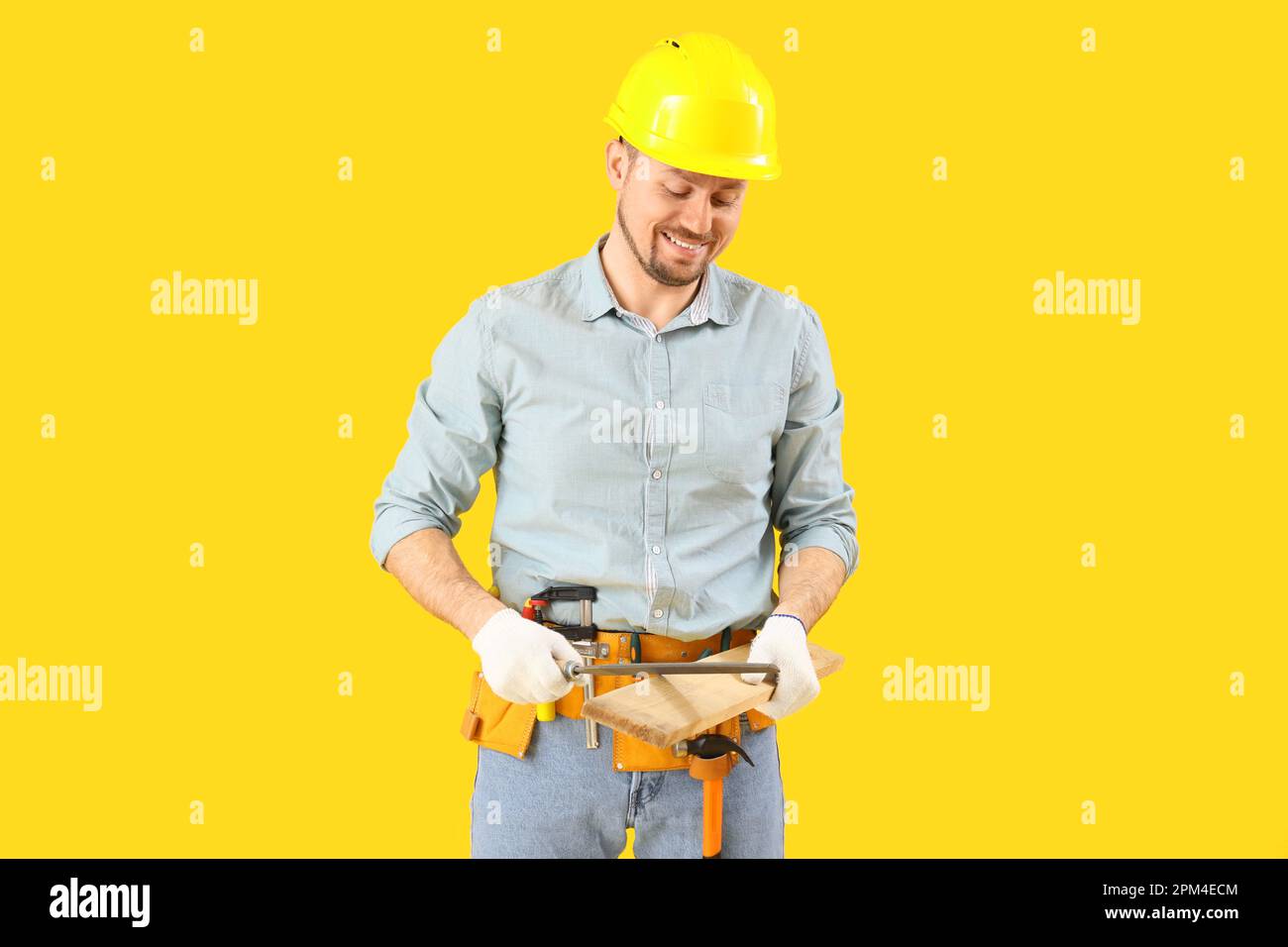 Male carpenter sharpening wooden plank with file on yellow background ...