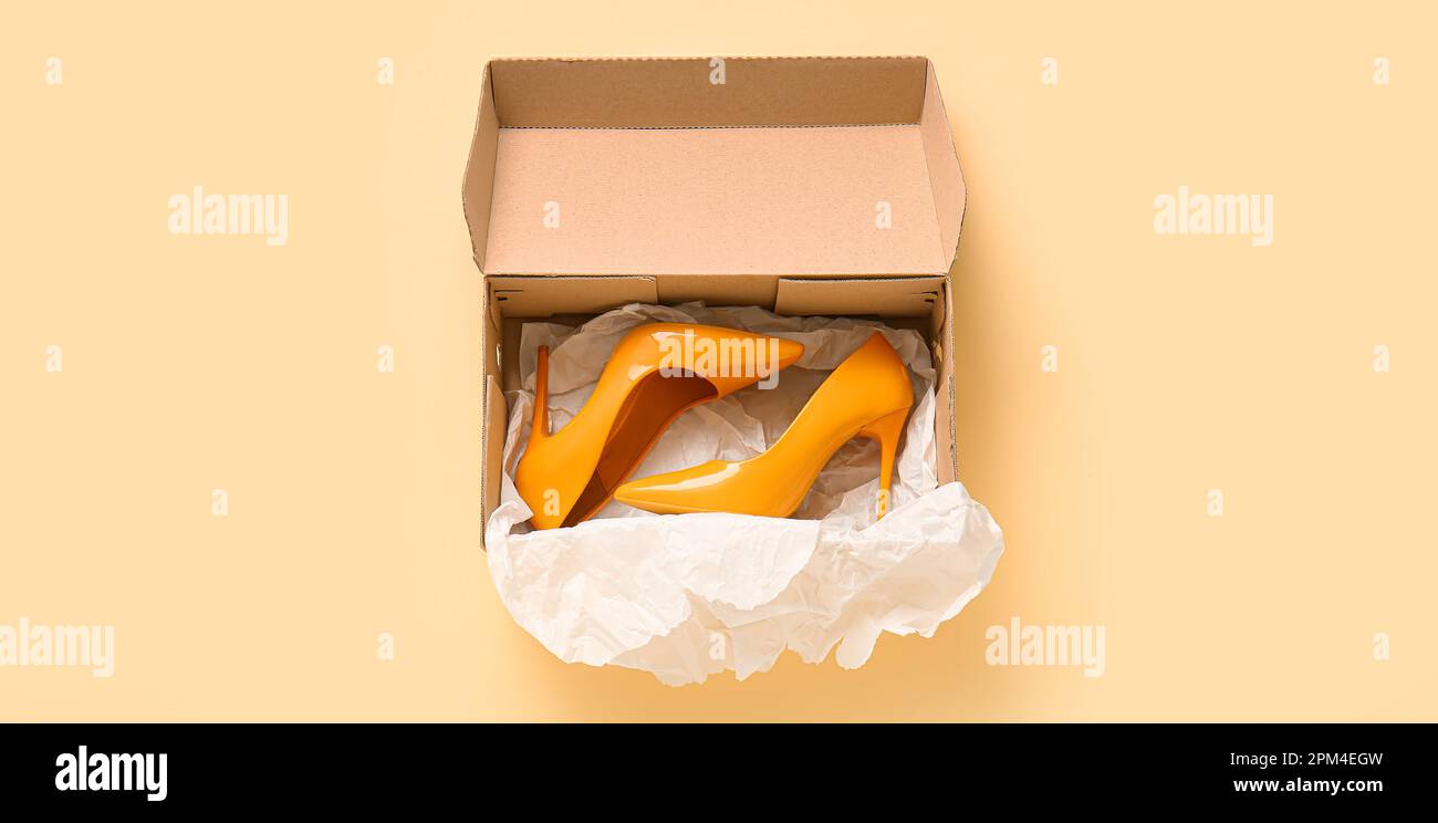 Cardboard box with high heeled shoes on beige background Stock Photo ...