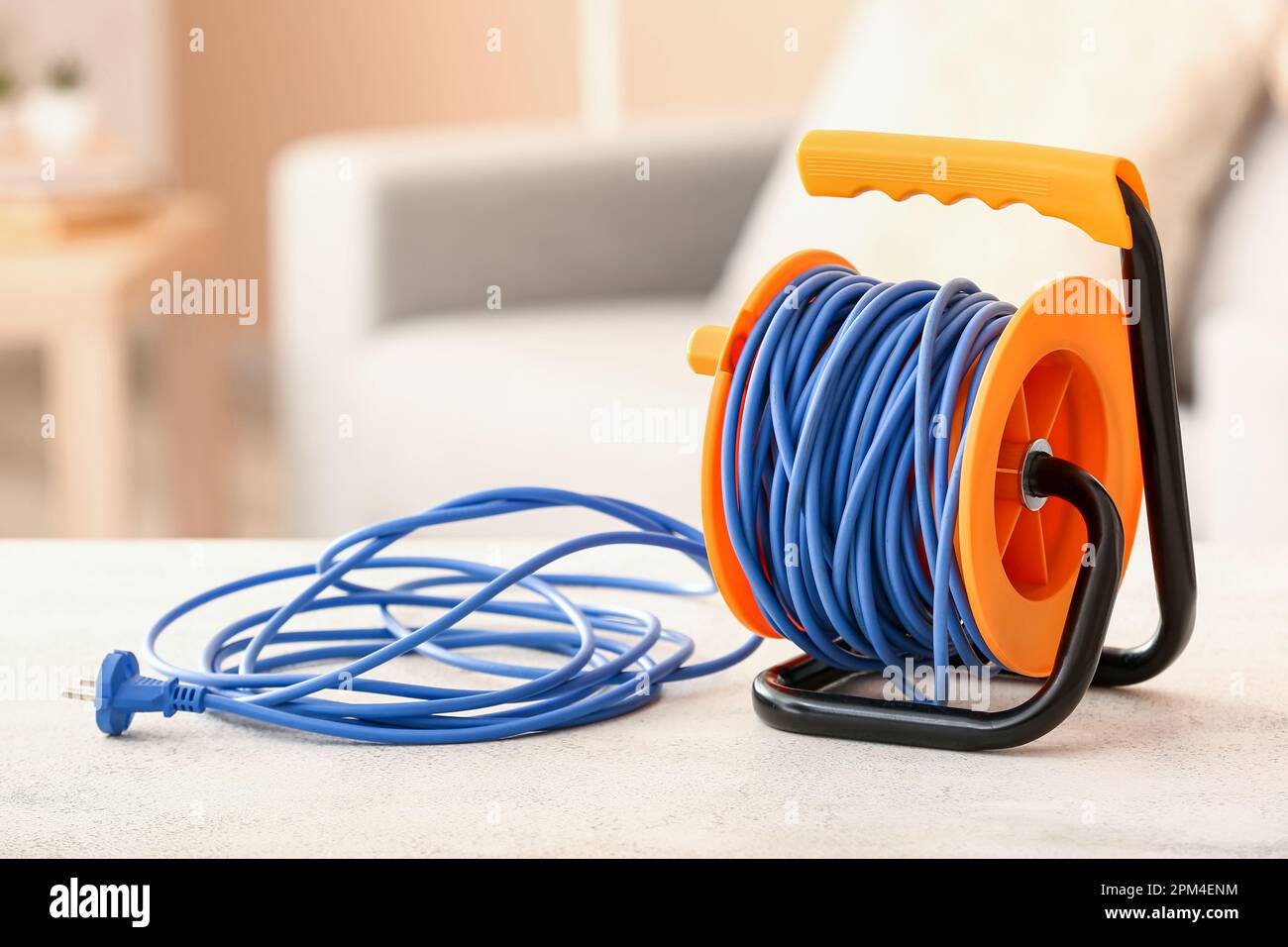 Extension electric cable reel on table in room Stock Photo - Alamy