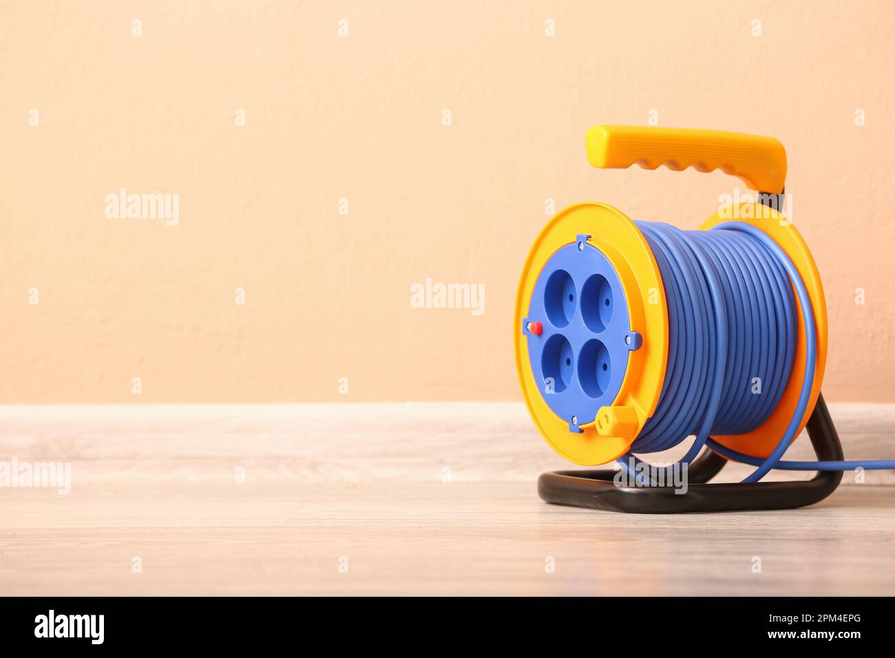 Extension electric cable reel on floor near color wall Stock Photo - Alamy
