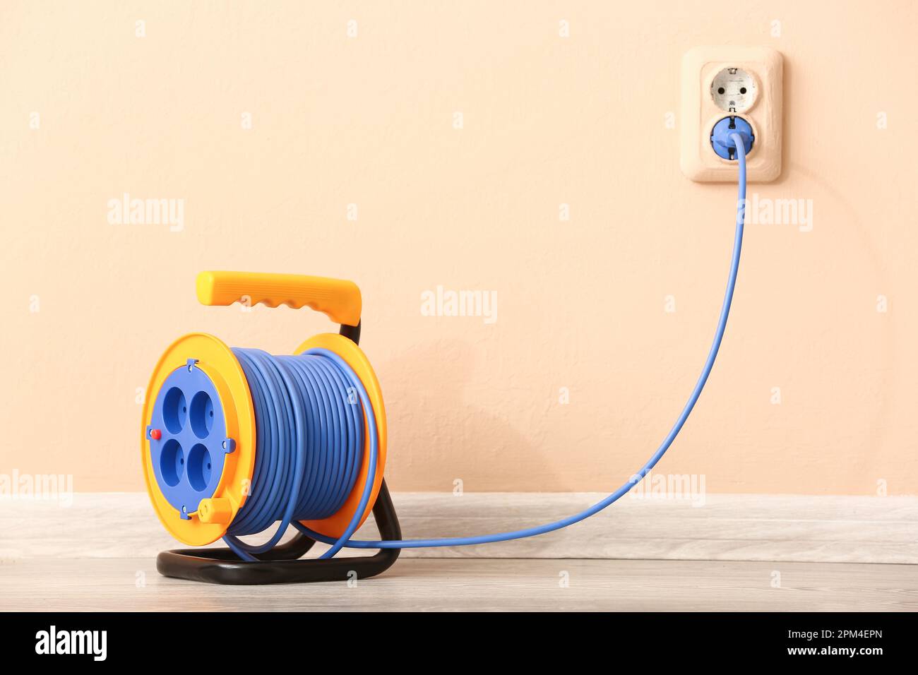 Extension electric cable plugged into socket near color wall Stock ...