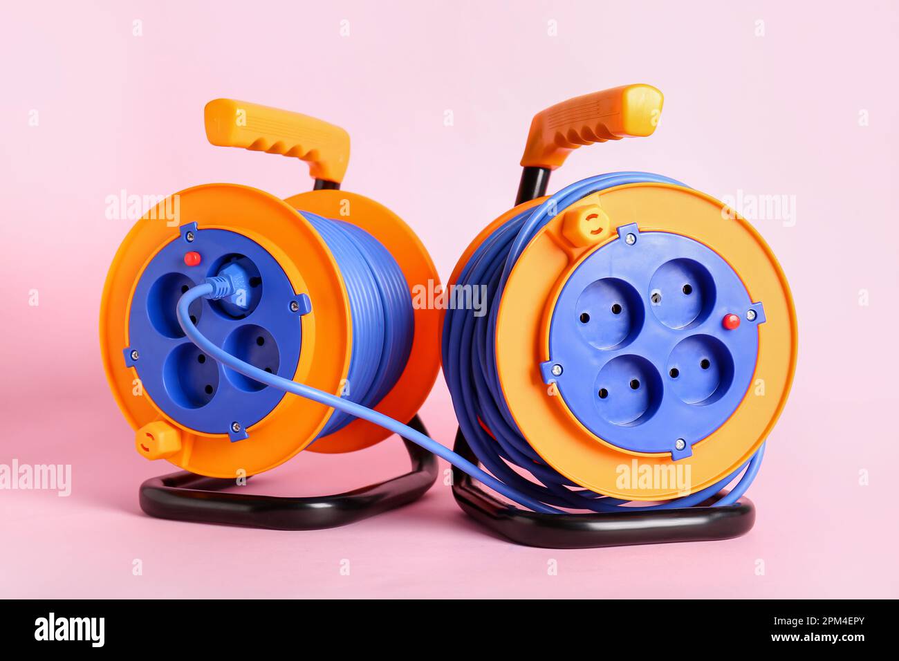 Extension electric cable reels on pink background Stock Photo - Alamy