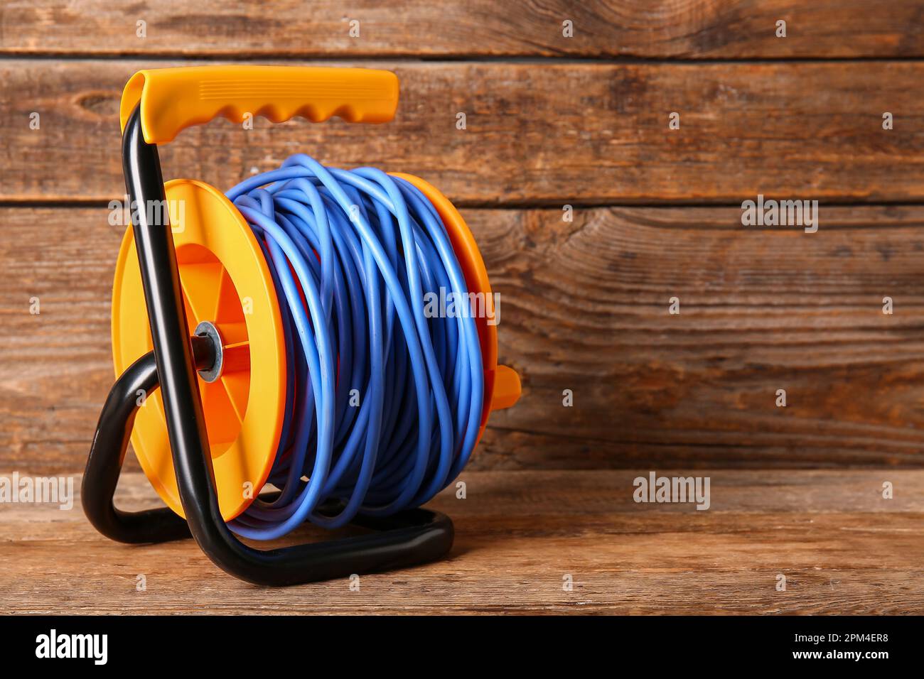 Extension electric cable reel on wooden background Stock Photo - Alamy