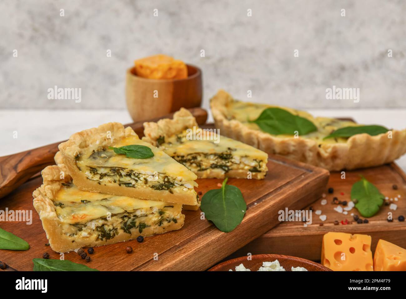 Board with pieces of delicious quiche on white table Stock Photo - Alamy
