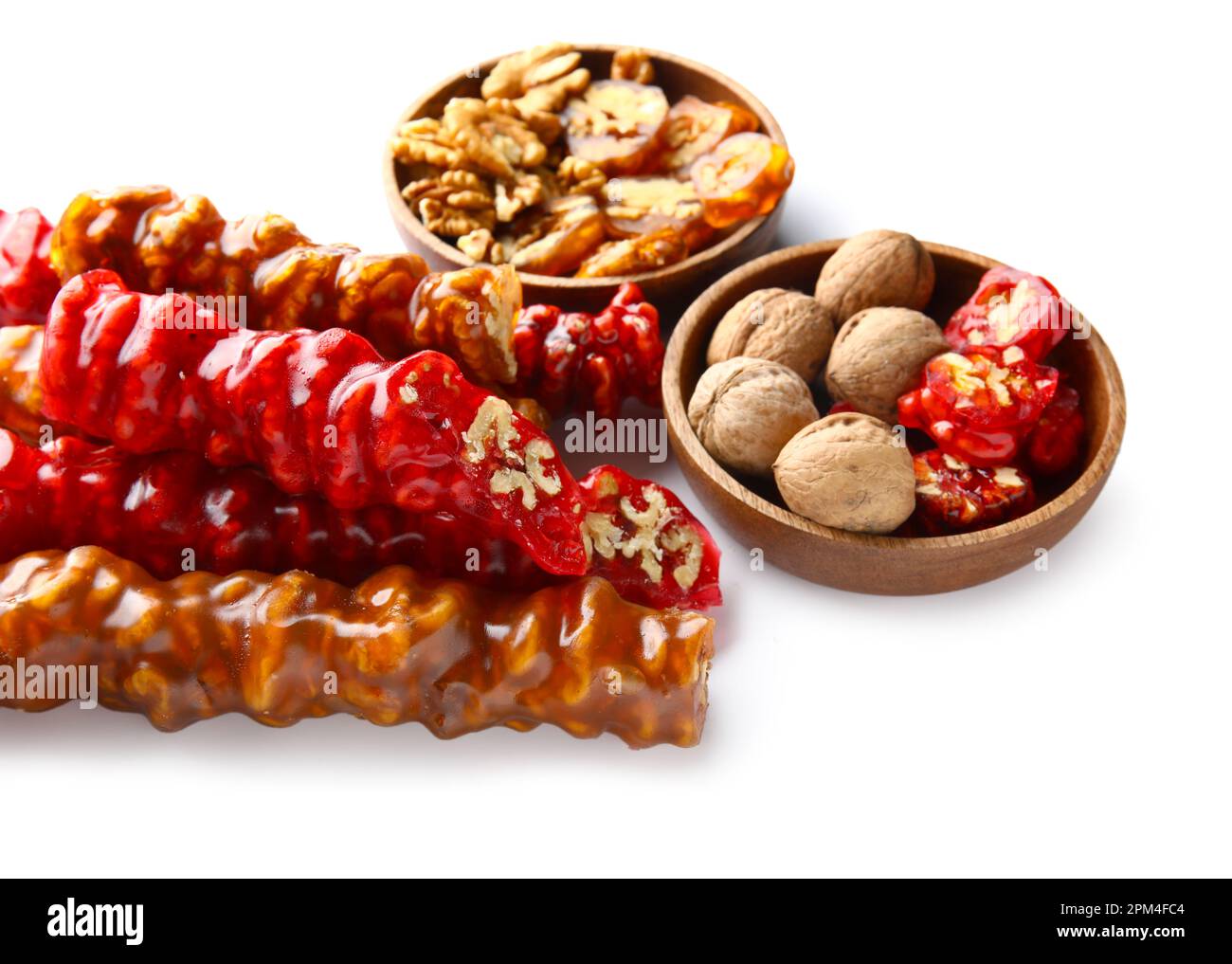 Delicious churchkhela and bowls with walnuts isolated on white ...