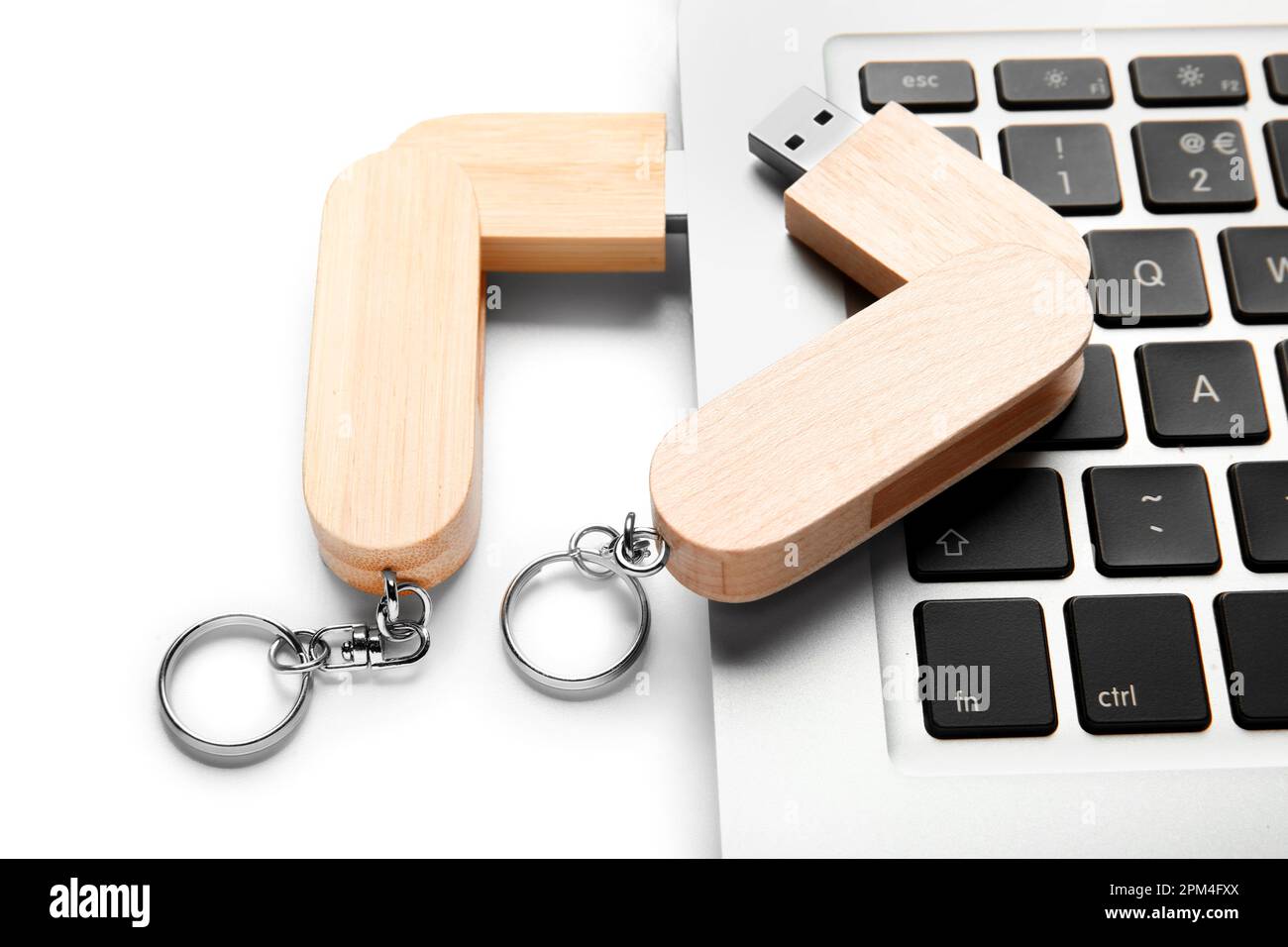 Modern laptop with wooden USB flash drives isolated on white background ...