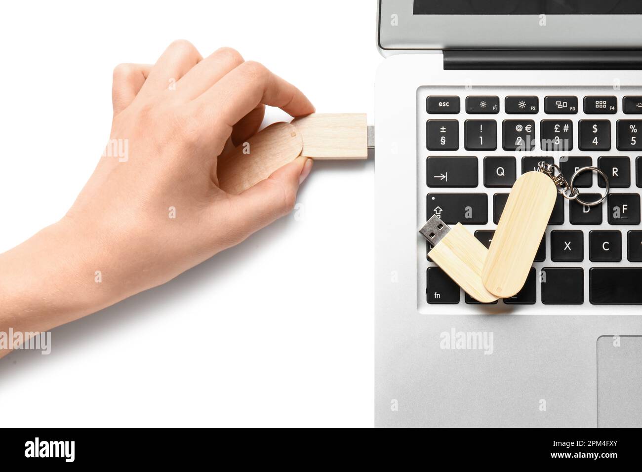 Woman using wooden USB flash drive with modern laptop isolated on white ...