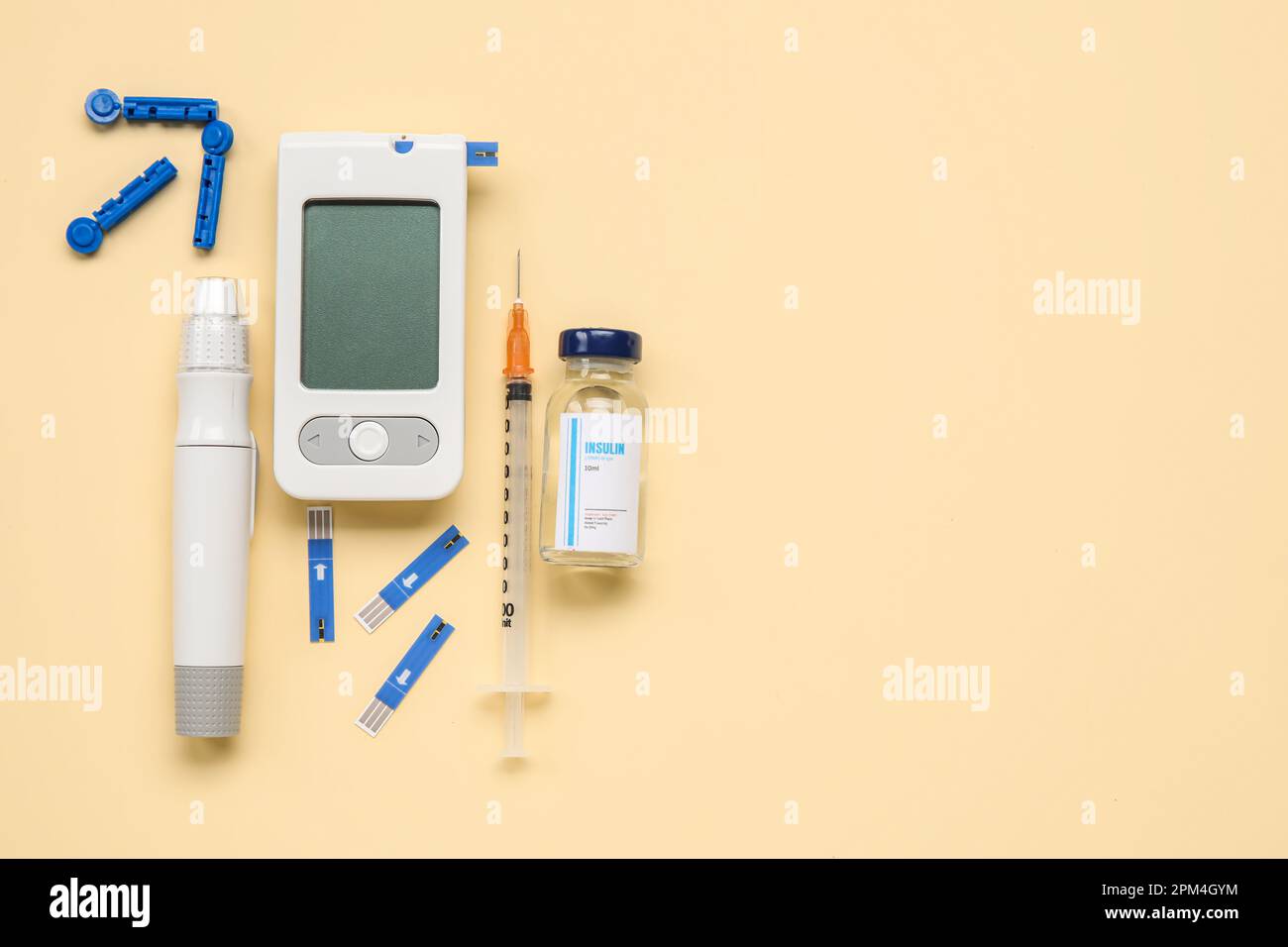 Glucometer with lancet pen, insulin and syringe on beige background ...