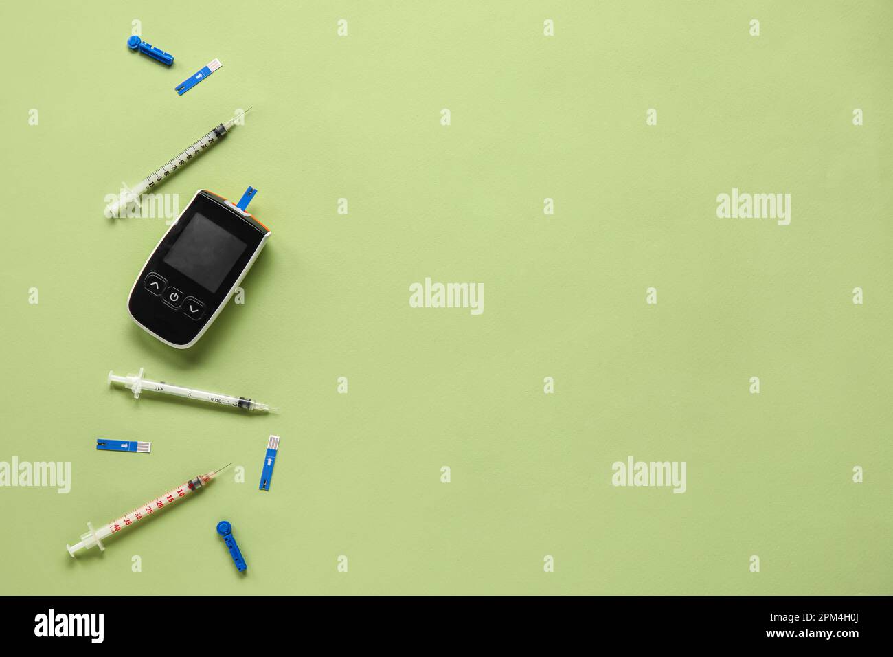Glucometer with strips and syringes on green background. Diabetes ...