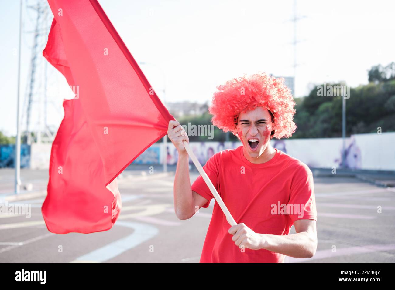 Soccer fan screaming and cheering for his team with a flag and his team ...