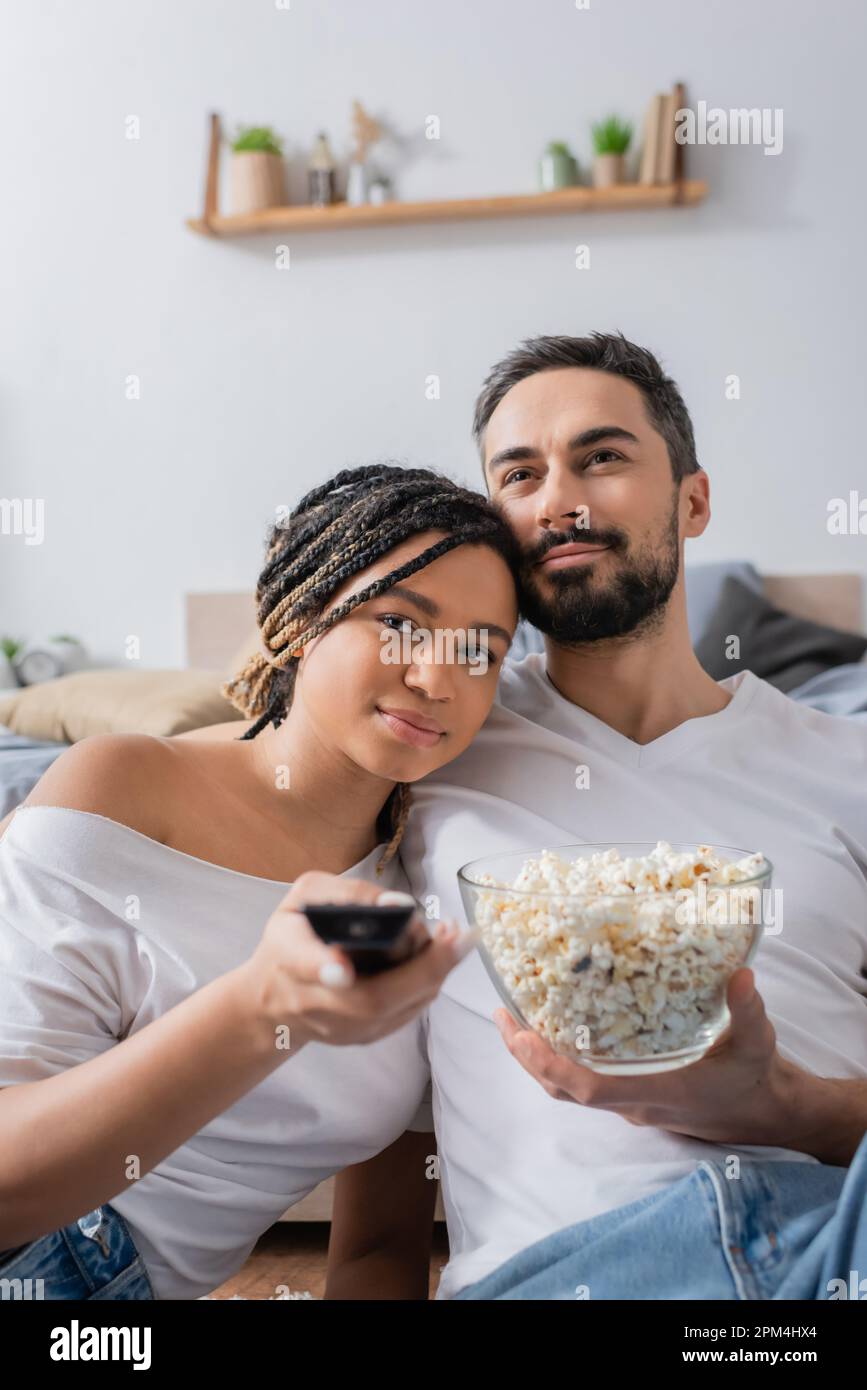 smiling african american woman with tv remote controller clicking tv ...