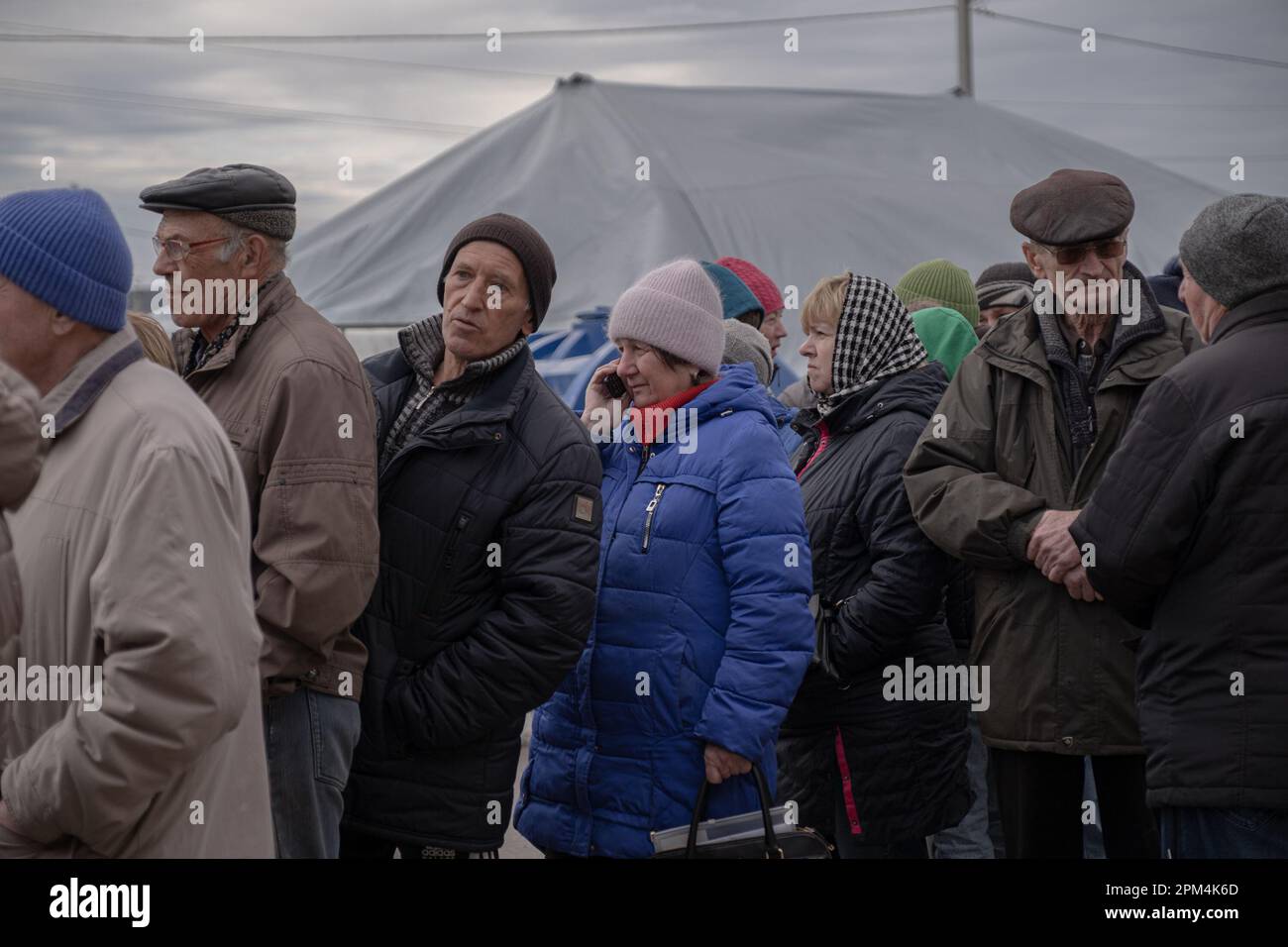 People wait in a queue for the distribution of humanitarian aid in the ...