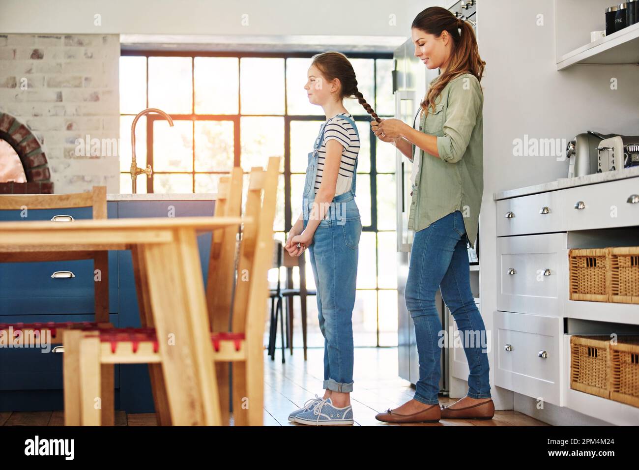 Mom aka hair stylist. a happy mother braiding her daughters hair at home Stock Photo - Alamy