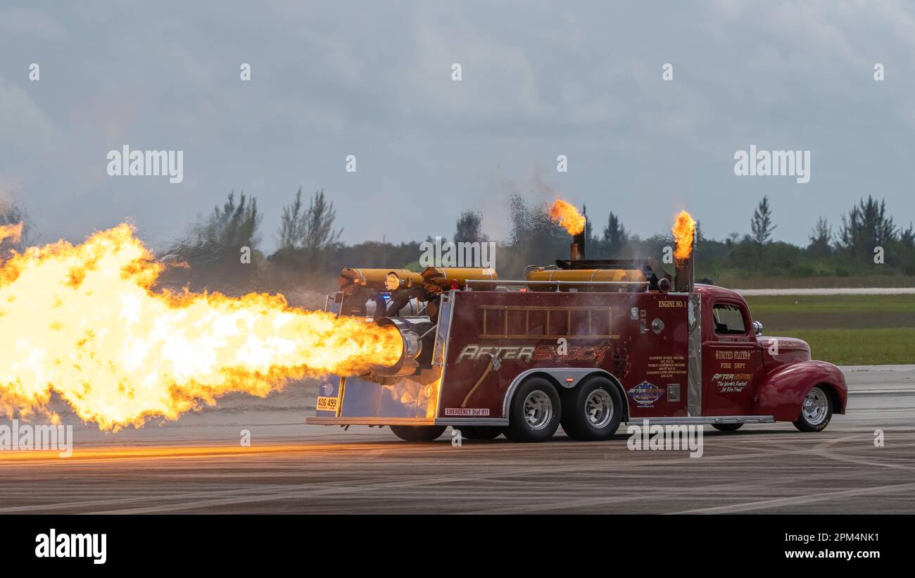 A fire truck with a tall ladder and a large flame pattern on top is ...
