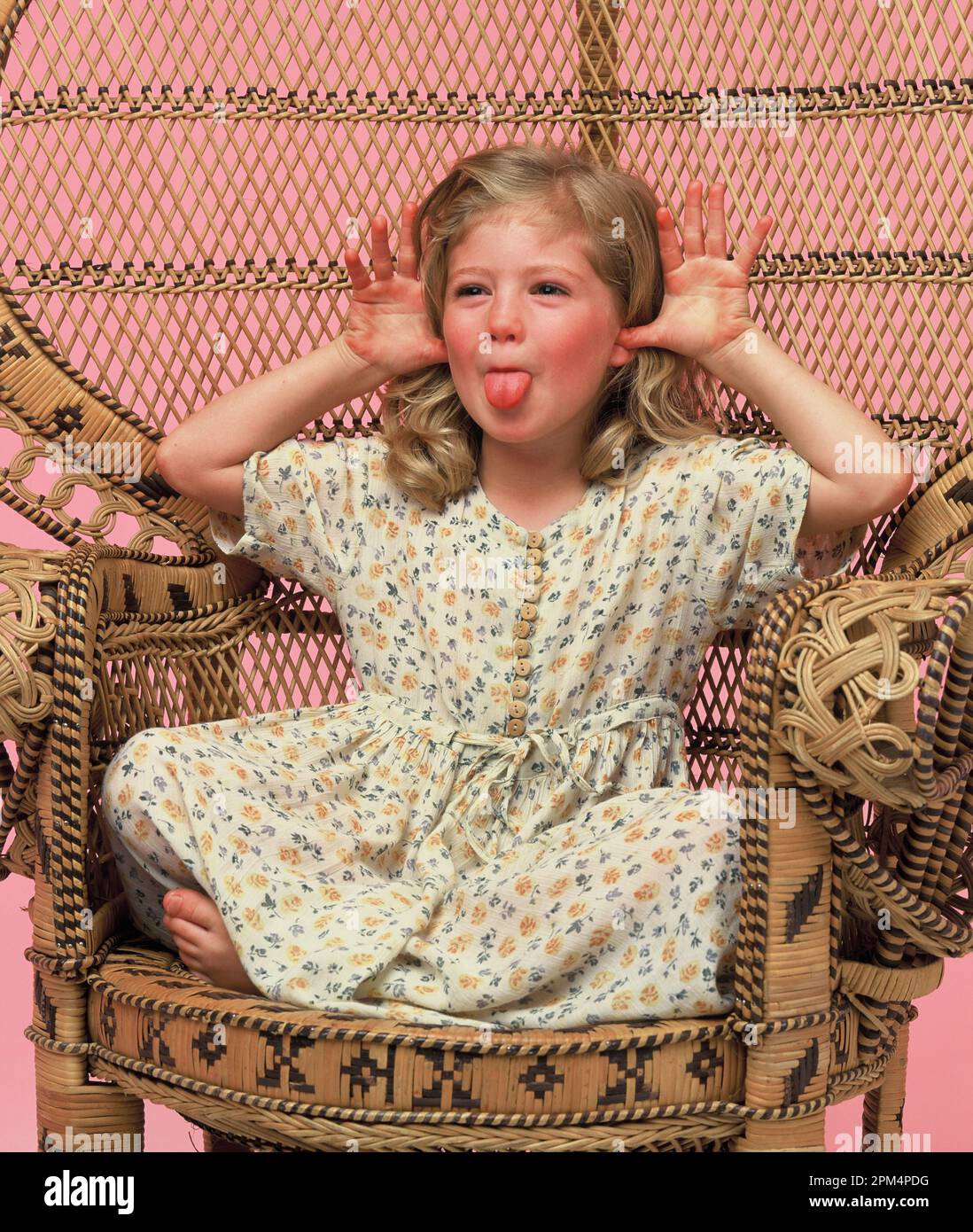 Studio portrait of young girl child blowing a raspberry, sitting in ...