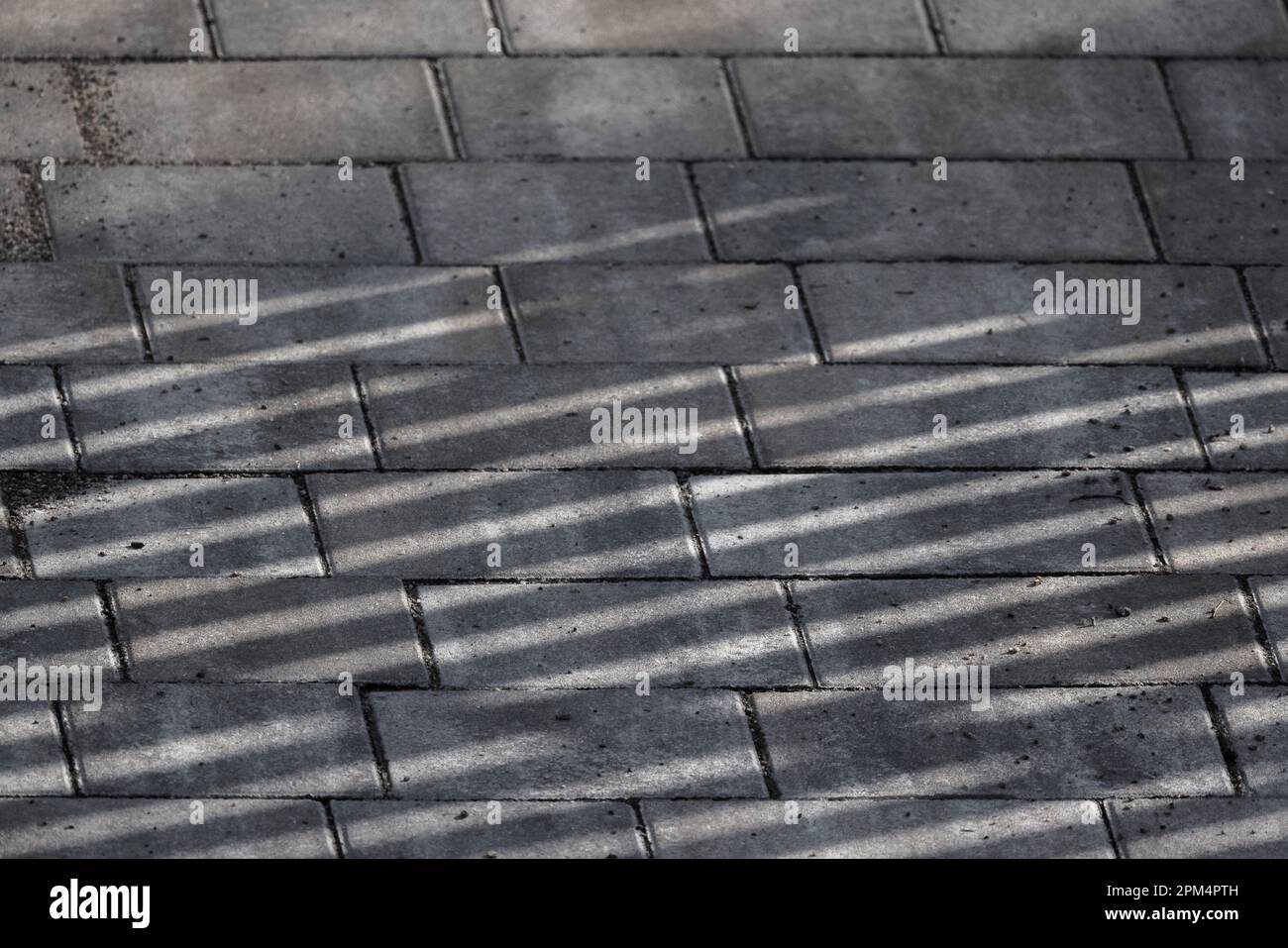 Gray concrete cobble road with striped shadows pattern, paving slabs ...