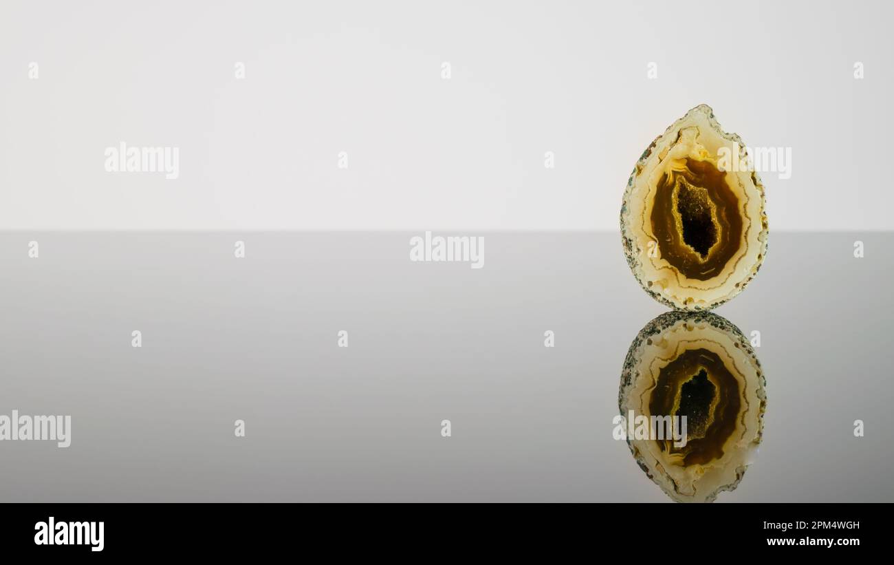 A yellow geode rock crystal with its reflection against a grey ...