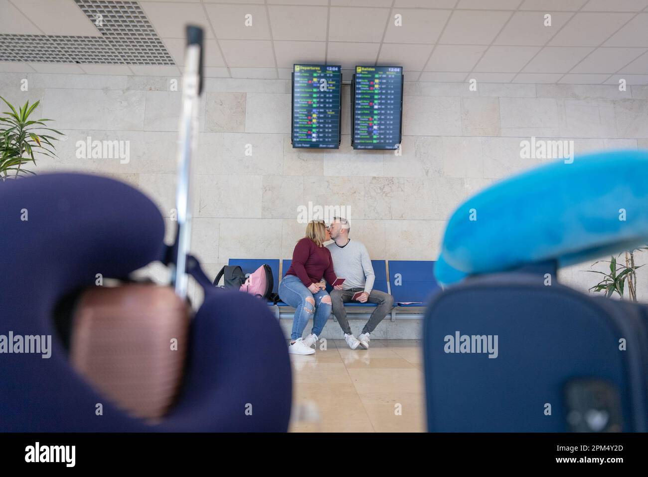 A couple is kissing while at the airport about to board their plane ...