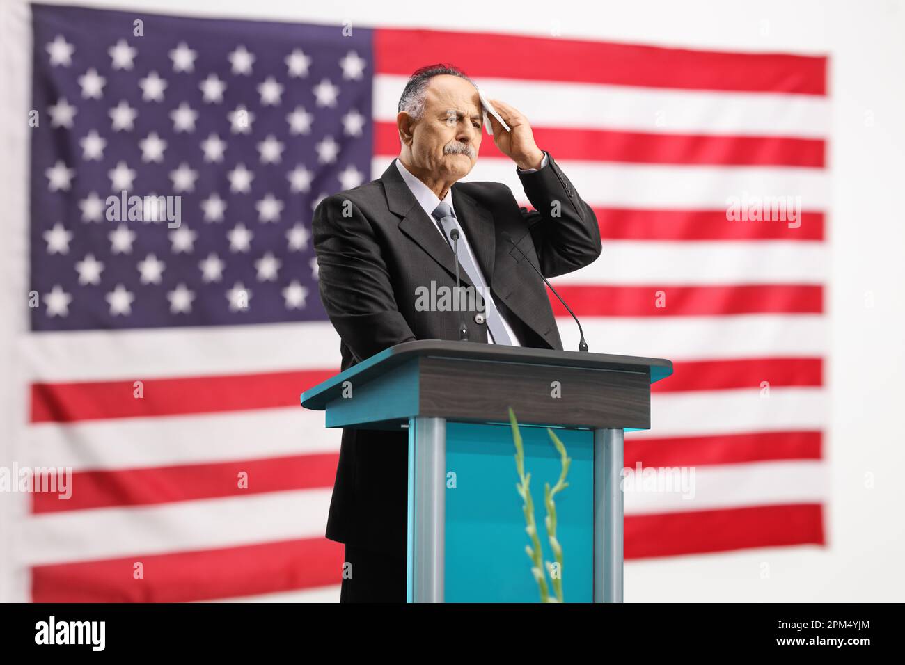 Nervous politician at a speech podium wiping forehead with the USA flag ...