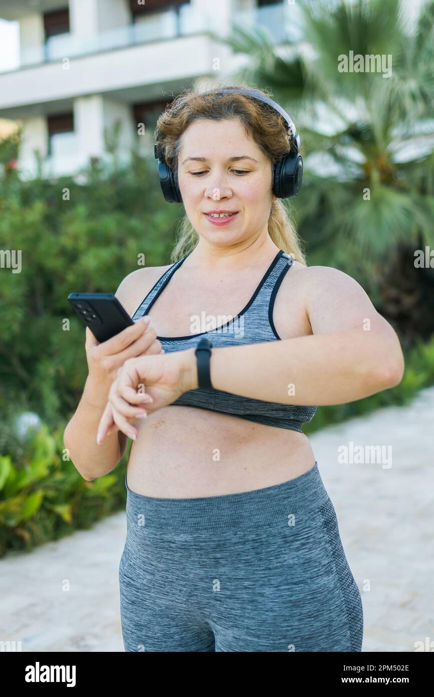 Fat woman checking time or heart rate from smart watch. Exercise or ...