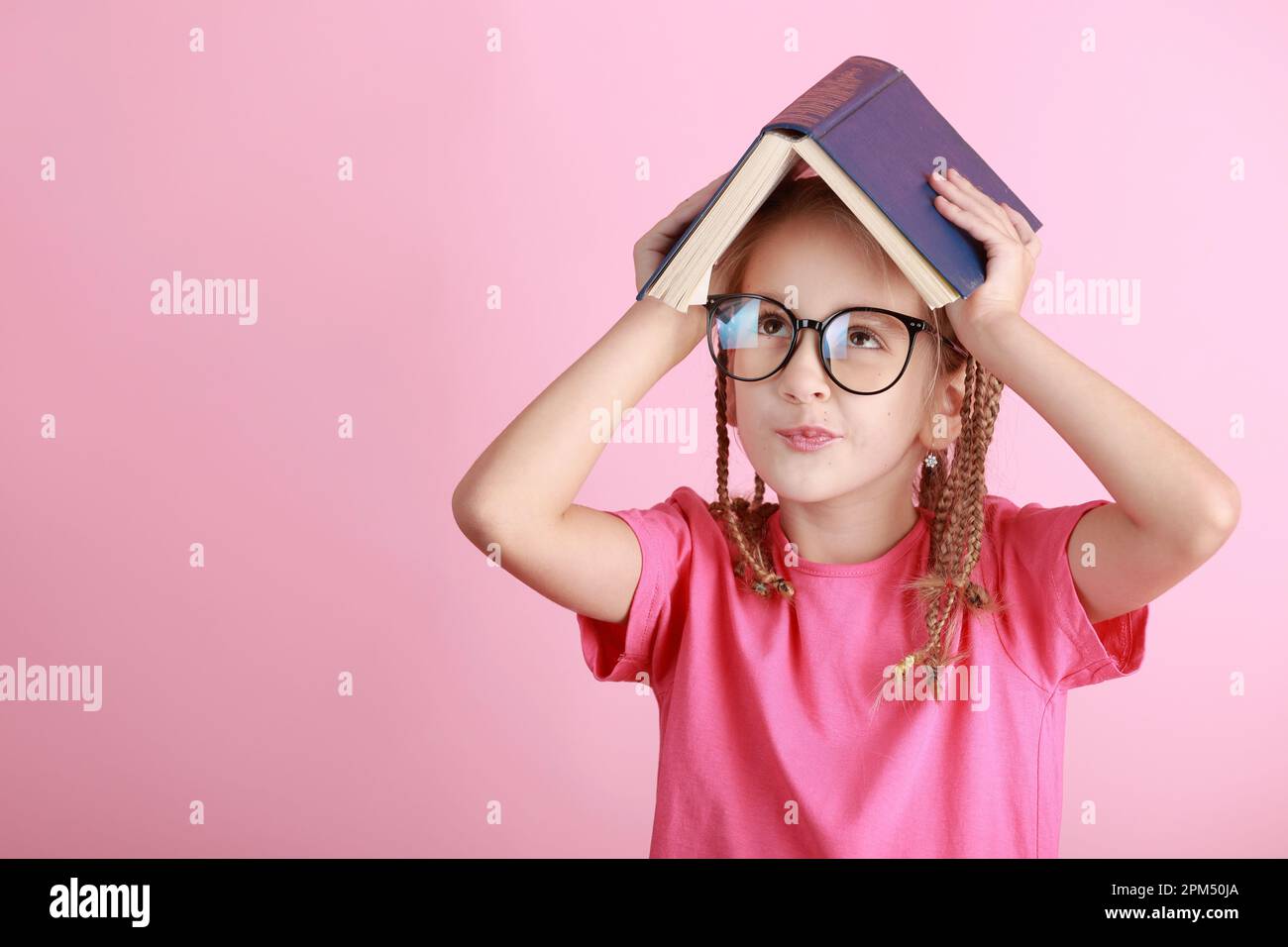 Back to school concept. Smiling pretty little school girl in glasses is ...