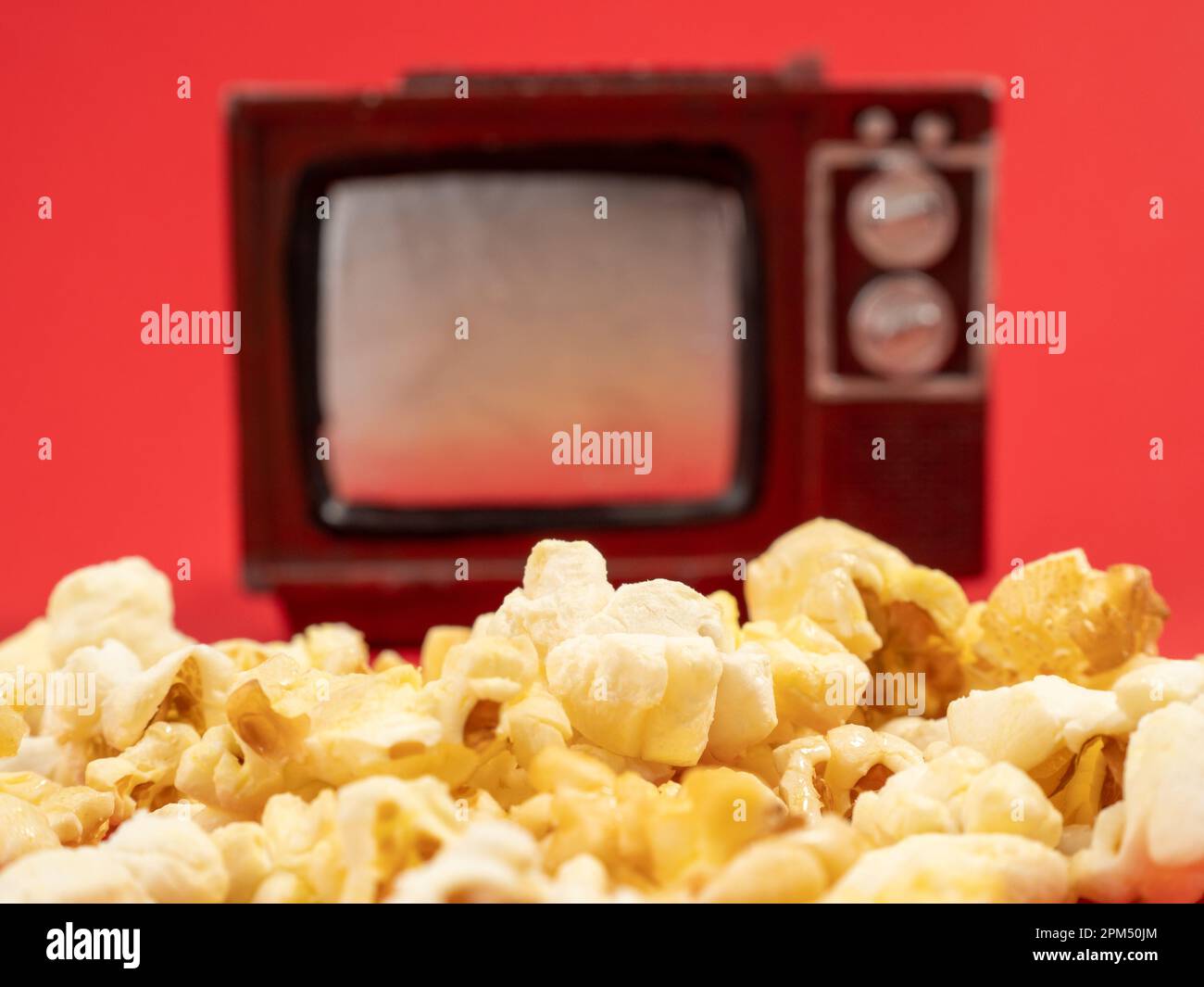Popcorn and an old TV on a red background. Sweet popcorn on red. Close ...
