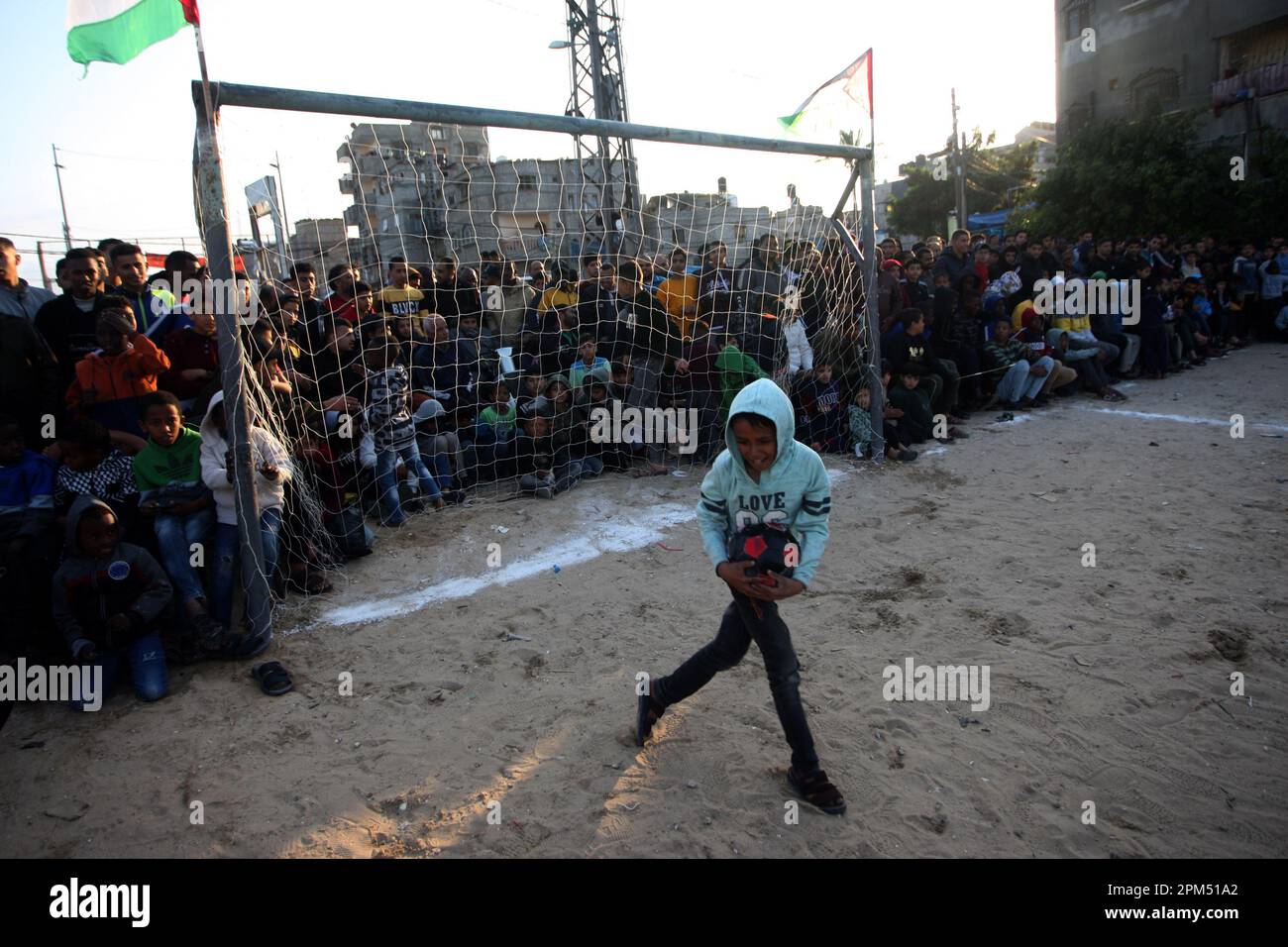 Palestinians watch youths play in a local football match in Popular ...