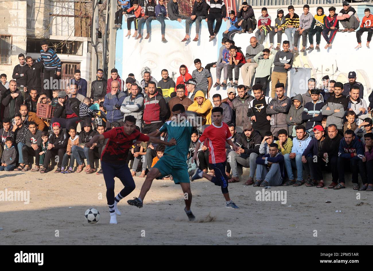 Palestinians watch youths play in a local football match in Popular ...