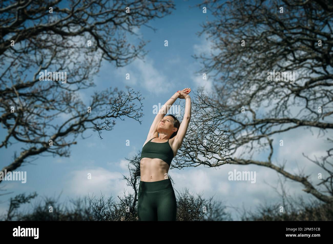 Sporty, mid adult woman doing stretching exercises outside in the park ...