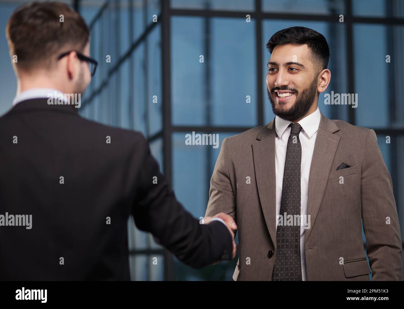 employees greeting each other with a handshake in the office corridor ...