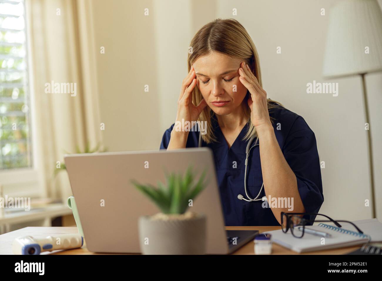 Tired female doctor using laptop while working at doctor's office ...