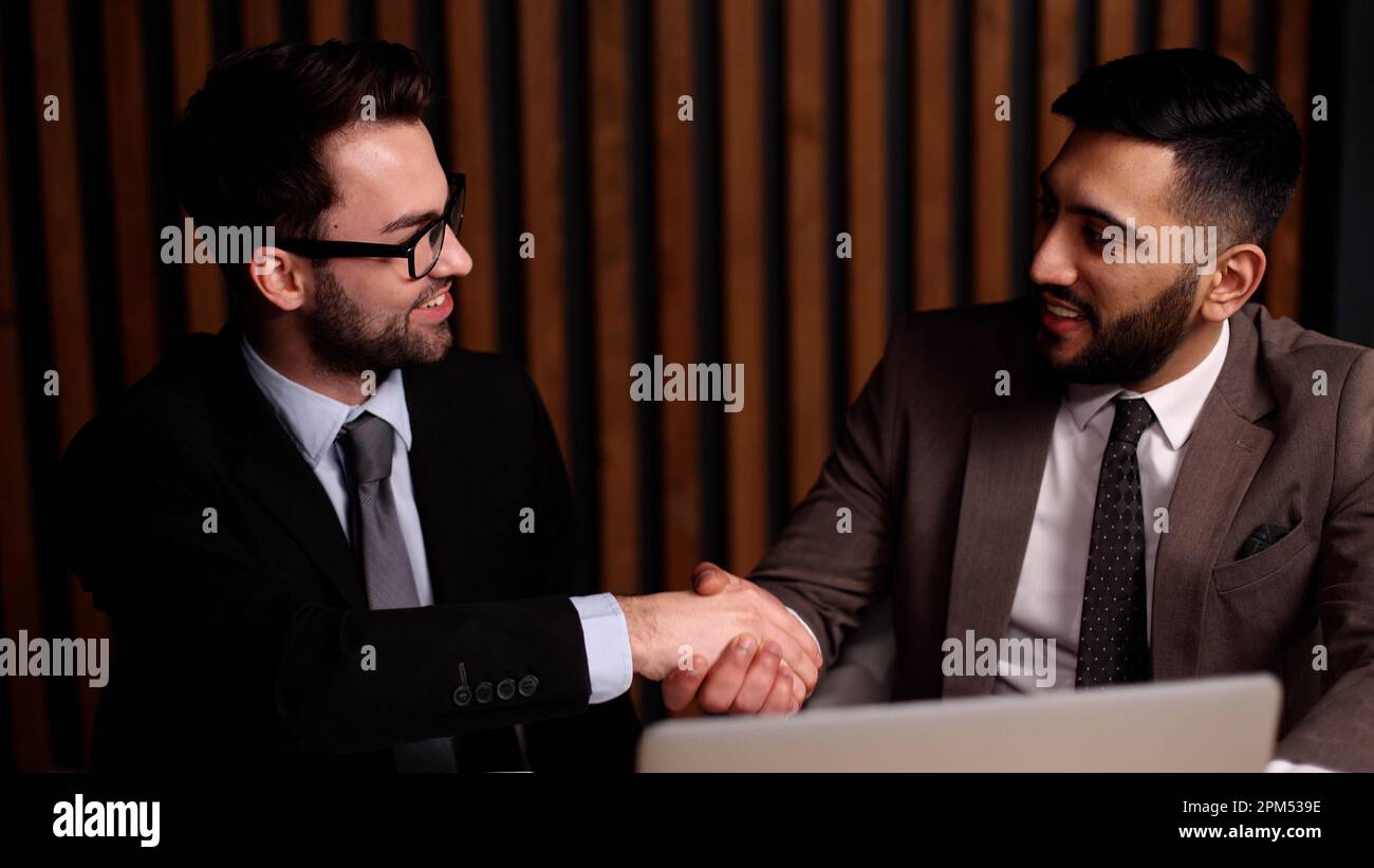 two men at the table shake hands Stock Photo - Alamy