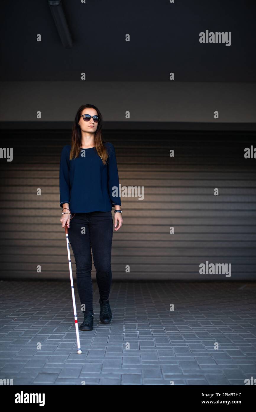 Young woman with impaired vision walking on city streets, using her ...