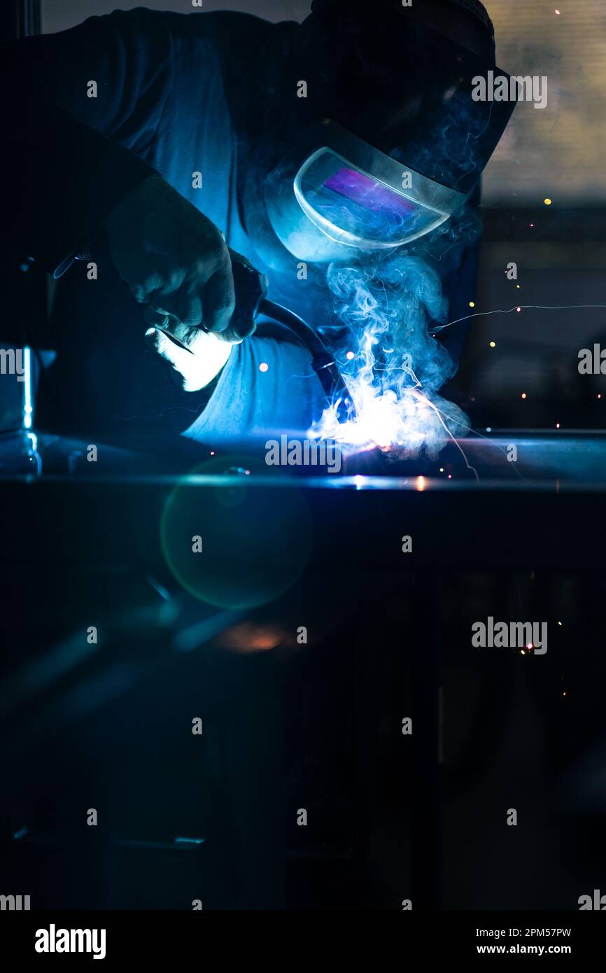 Man working on iron with grinder. Man at work. Sparkles and fire from ...