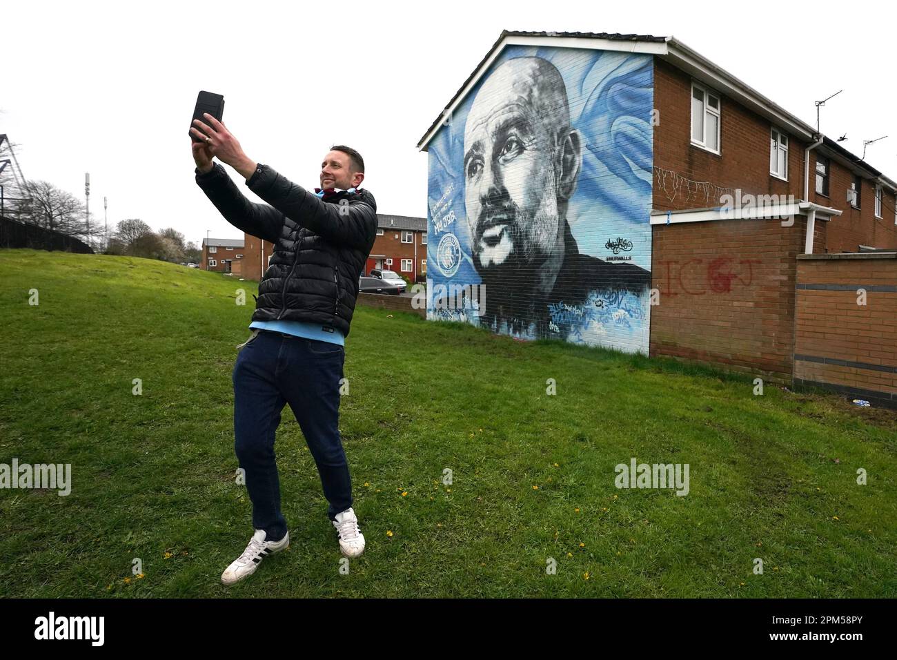 A Manchester City fan takes a photo of a mural of Manchester City ...
