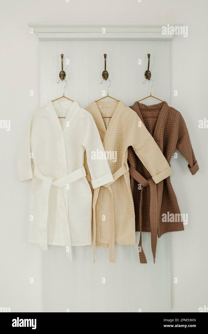 Three linen robes of different colors hang on a hanger in the bathroom ...