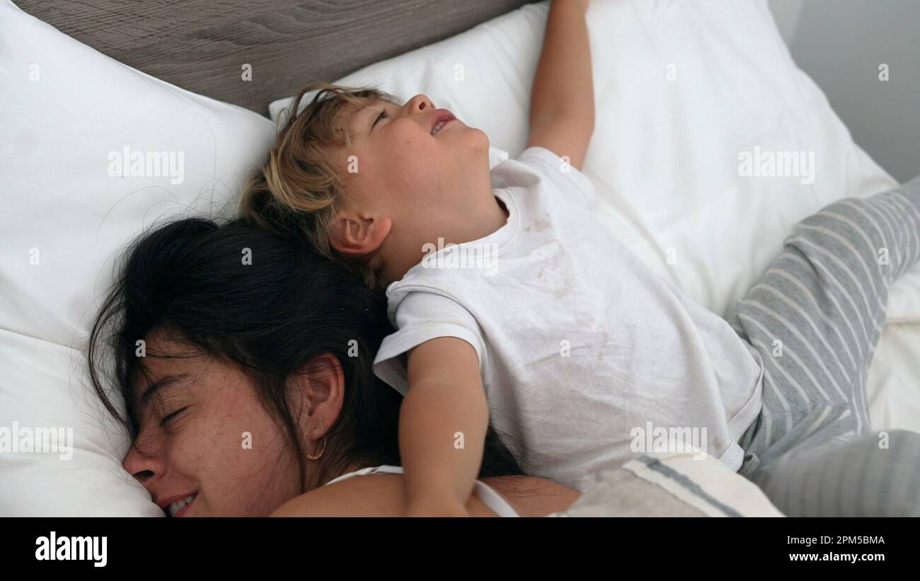 Little boy son trying to wake up mom in morning bed. Child waking up ...