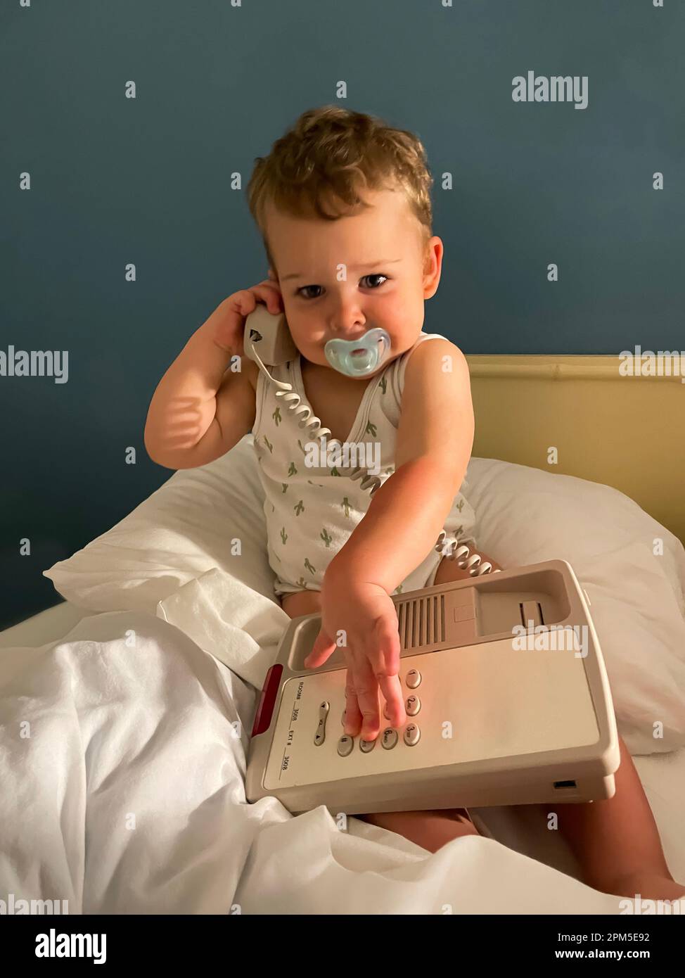baby boy with pacifier and telephone on bed looking in to camera Stock ...