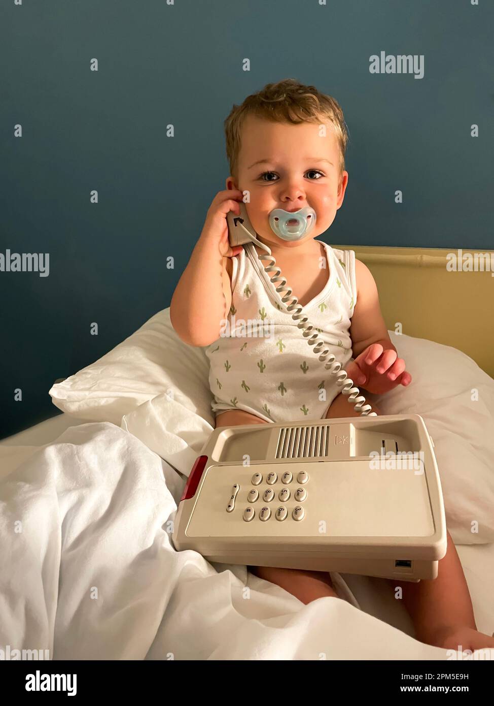 baby boy with pacifier and telephone on bed looking in to camera Stock ...